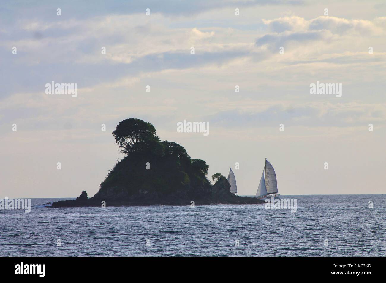 A scenic view of boats sailing in a vast ocean around a small island in ...