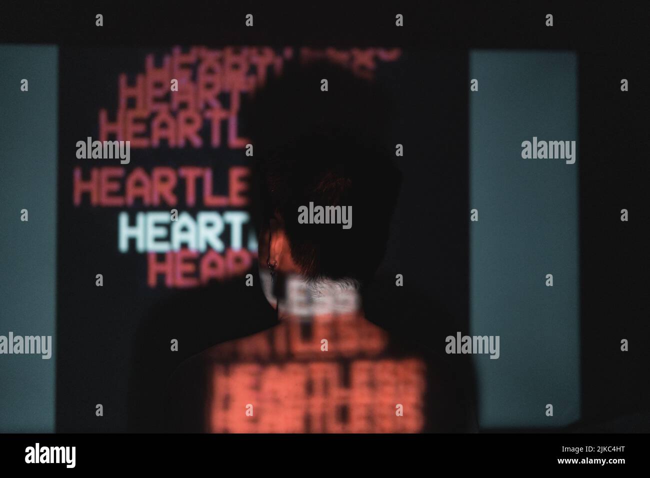 A projector photography with 'Heartless' text and human shadow in black ...