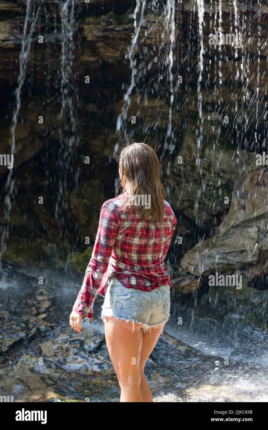 Beautiful young woman in cut off jeans and red flannel shirt beneath a ...