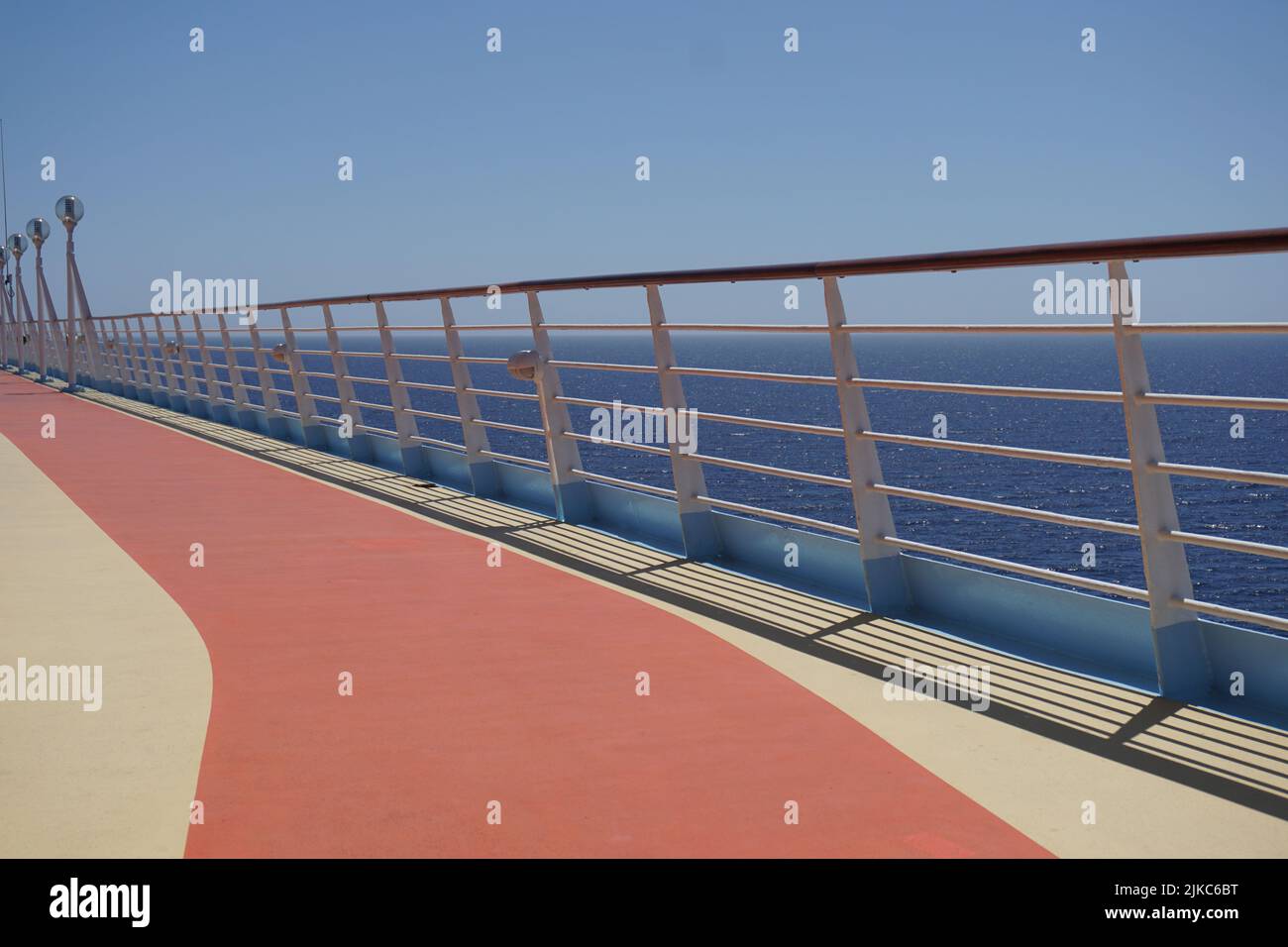 The empty deck of a cruise ship set against a blue sky and the ocean ...