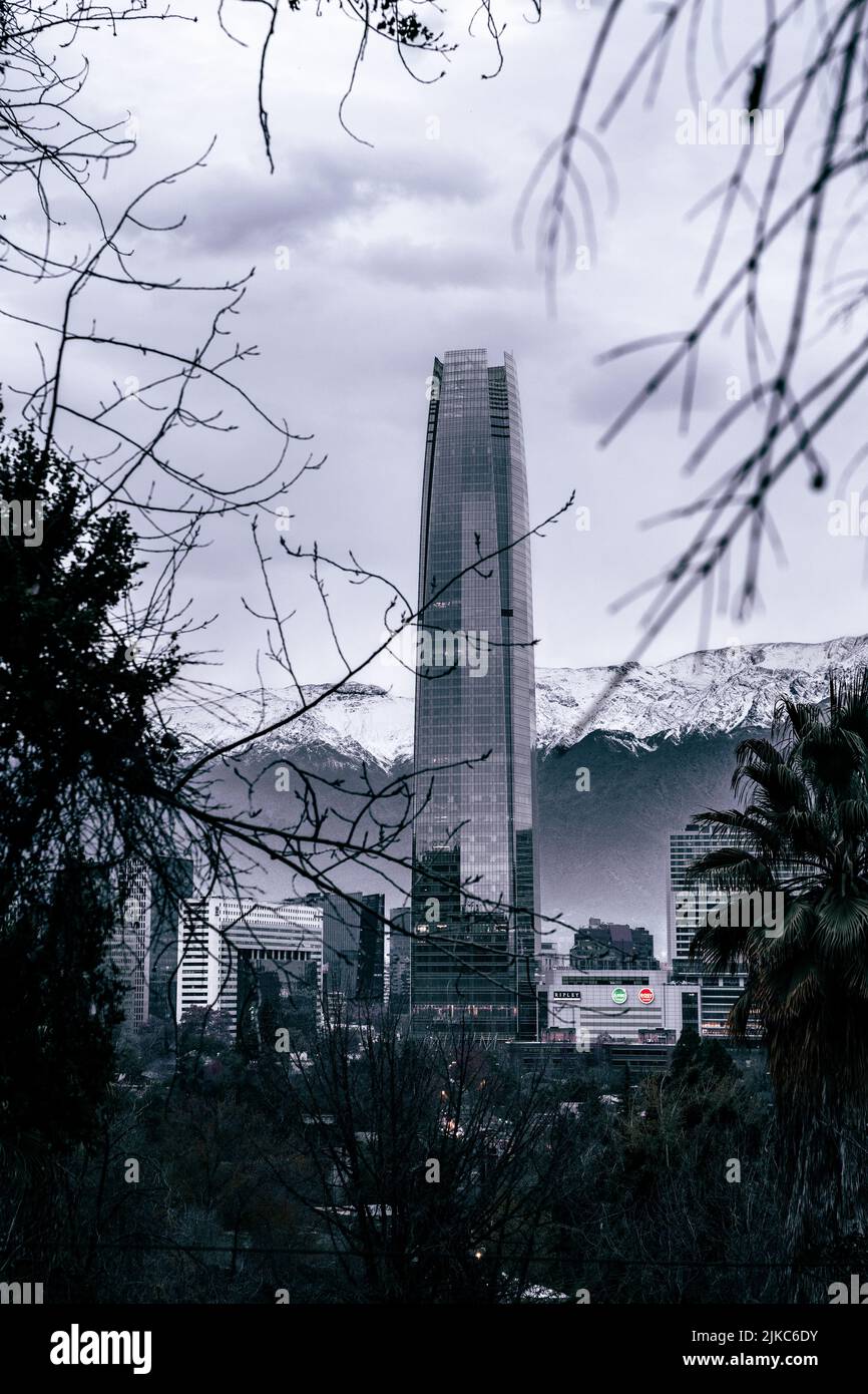 A vertical shot of Torre Costanera Center against snowy mountains under ...