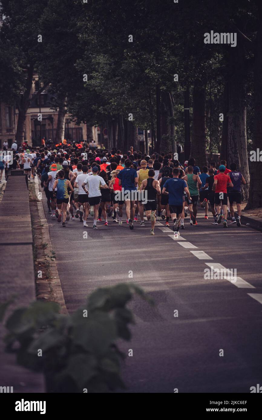 A vertical shot of many people running during an event on trail asphalt ...