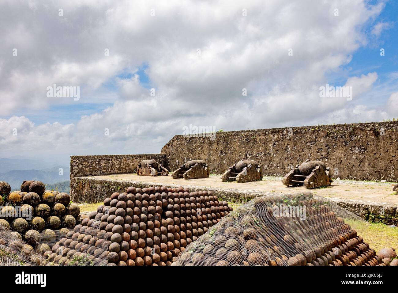 A piles of bullets and canons near an old wall on a cloudy morning ...