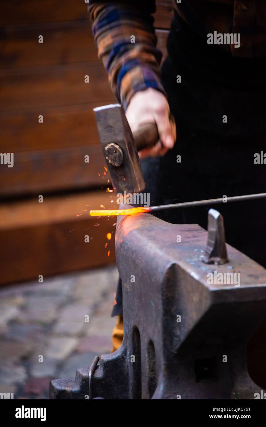 A man striking hot iron with a hammer on the Anvil Stock Photo - Alamy