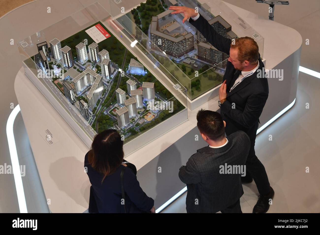 Moscow. Visitors at the model of a housing estate at an exhibition of ...