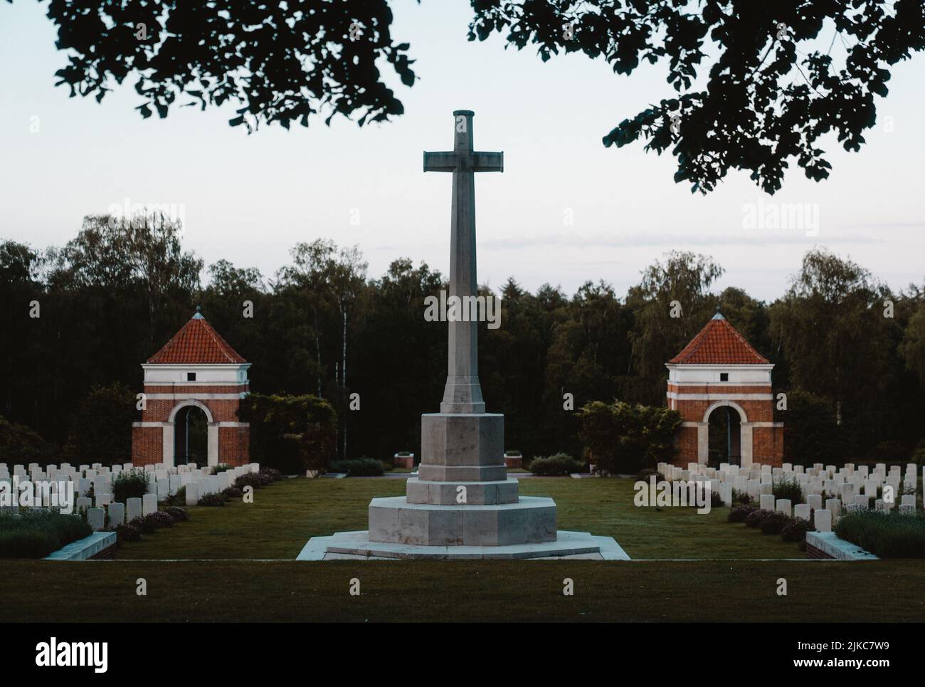 A cemetery with a cross statue in the center against trees Stock Photo ...