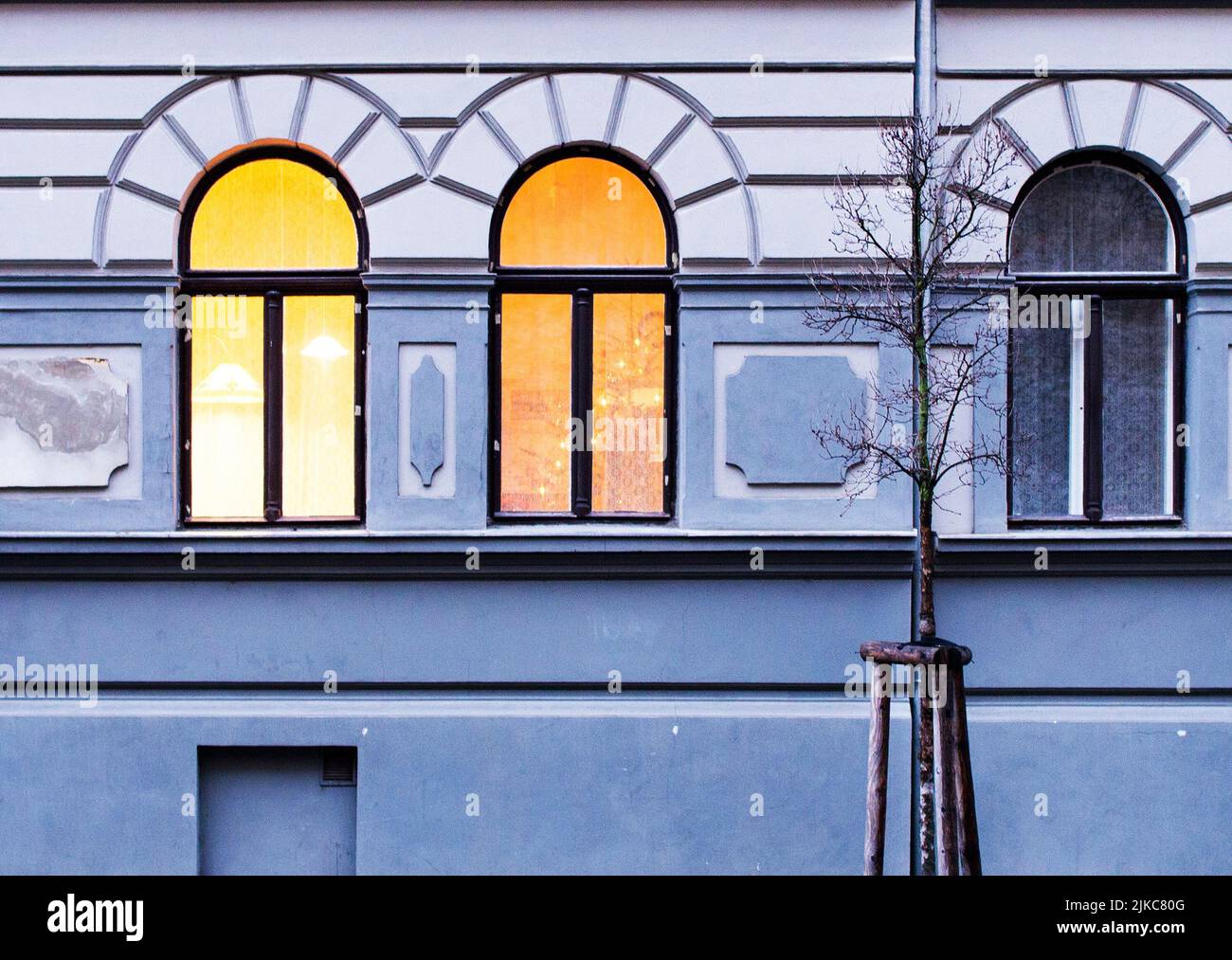 A facade of a modern building with turned on lights behind the windows ...