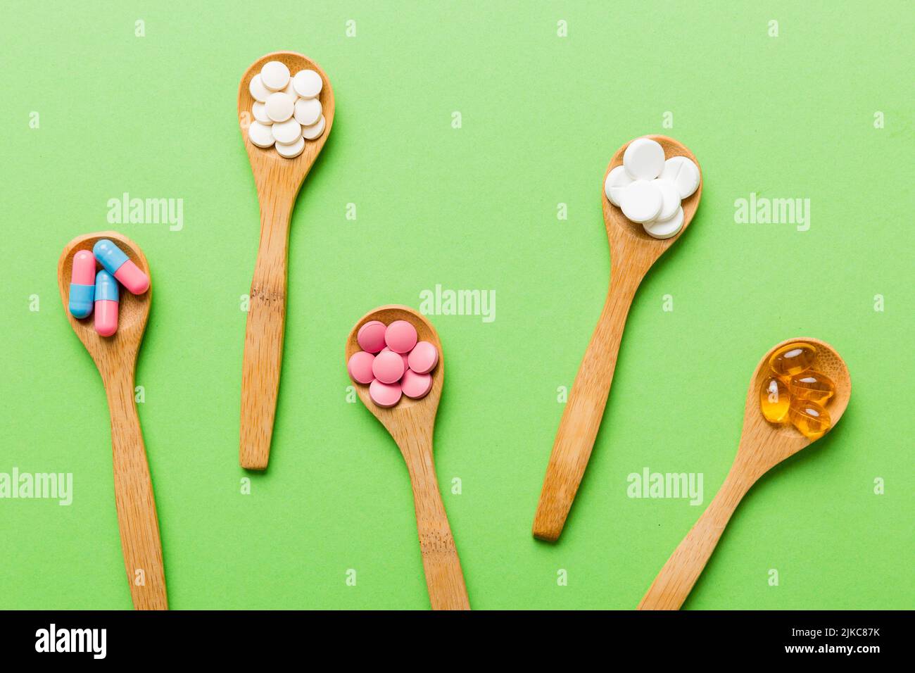 Vitamin capsules in a spoon on a colored background. Pills served as a ...