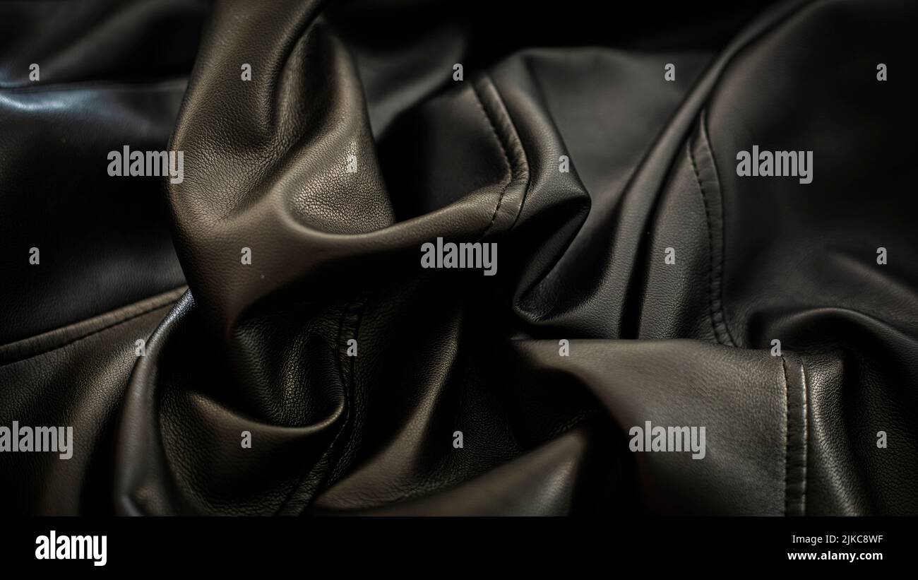 Black wrinkled leather jacket texture forming contrasts of light and ...