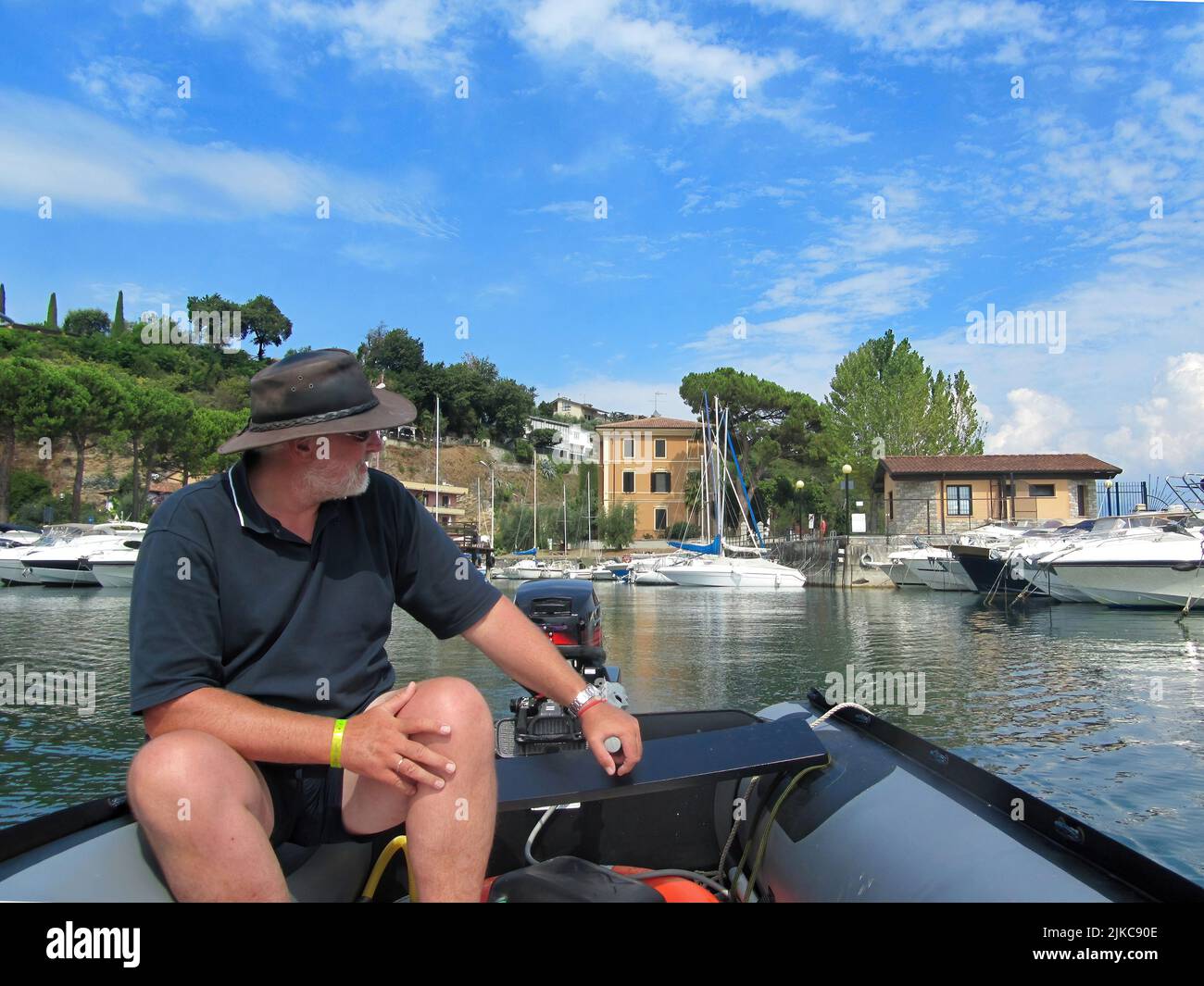 man driving an inflatable boat with outboard in front of a marina Stock ...