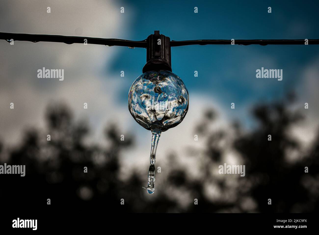 A shallow focus of a frozen ice piece hanging on a light bulb with ...