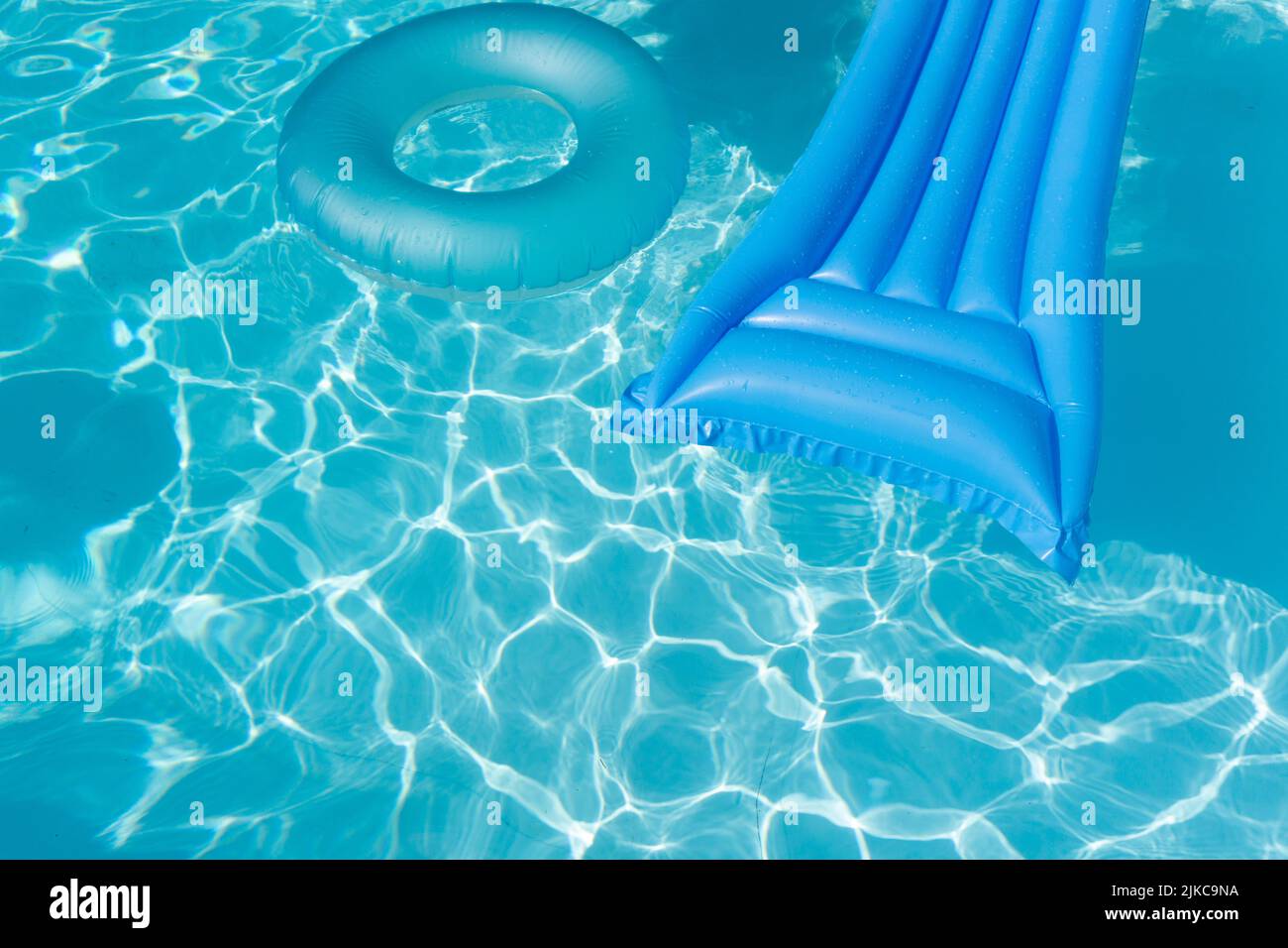 Bright blue summer pool lounger float on a rippled swimming pool Stock ...