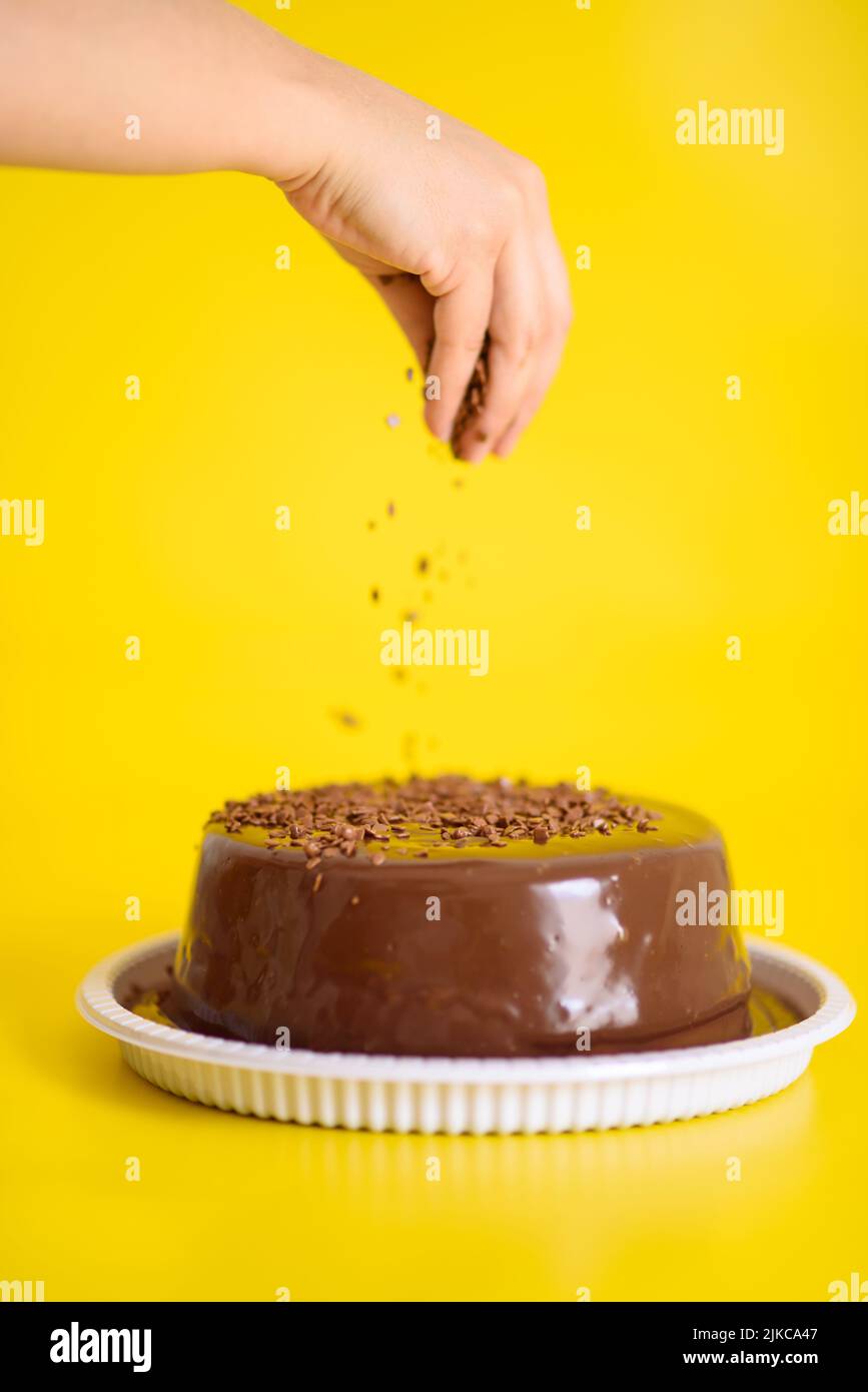 A vertical shot of a hand dropping chocolate crumbs on a simple ...