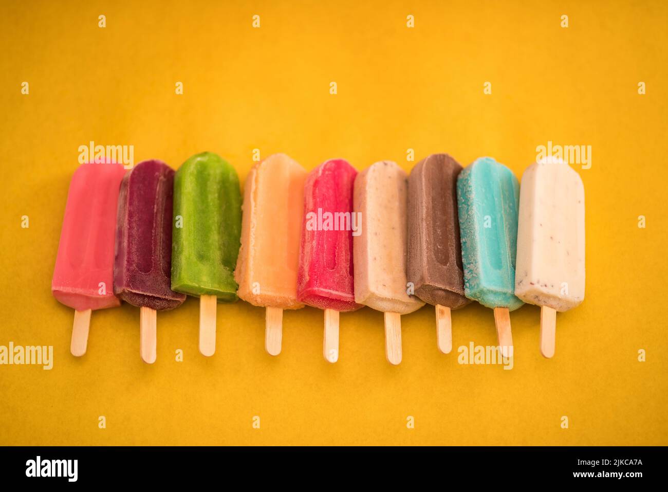 A Top view of colorful ice cream bars in row on the yellow background ...