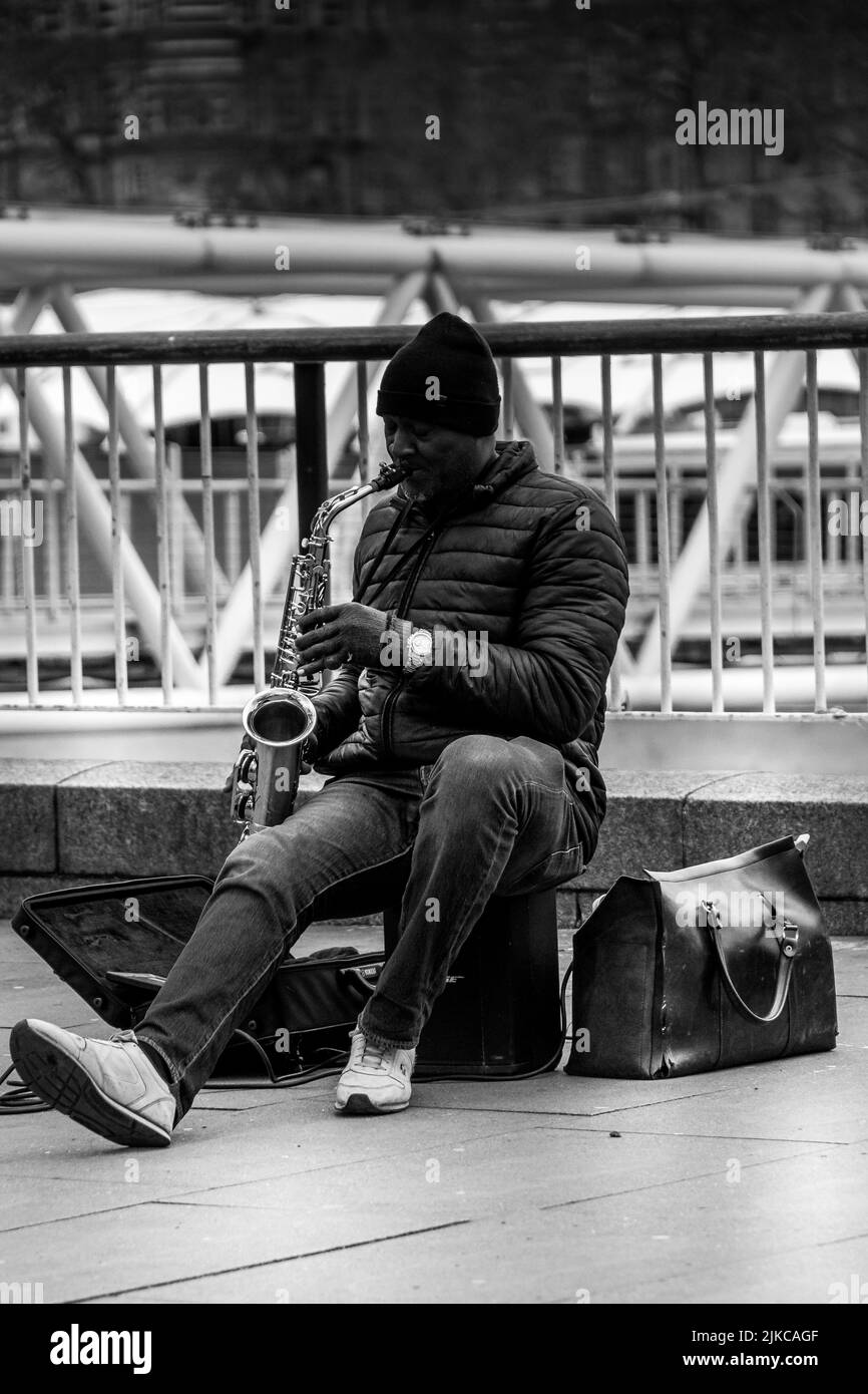A vertical of an Afro-American street artist playing the saxophone in ...