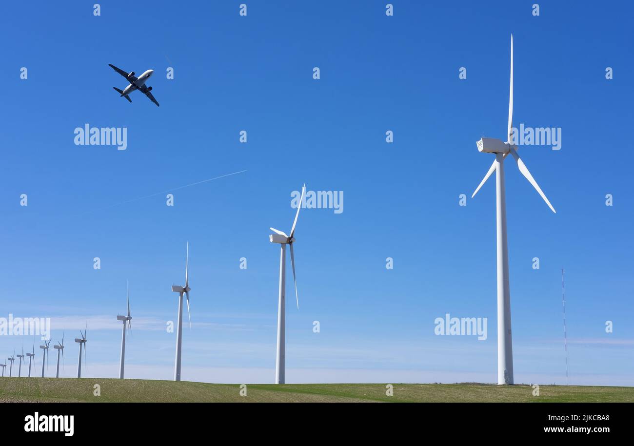 Airplane flying over a wind turbine farm. Renewable wind energy against ...