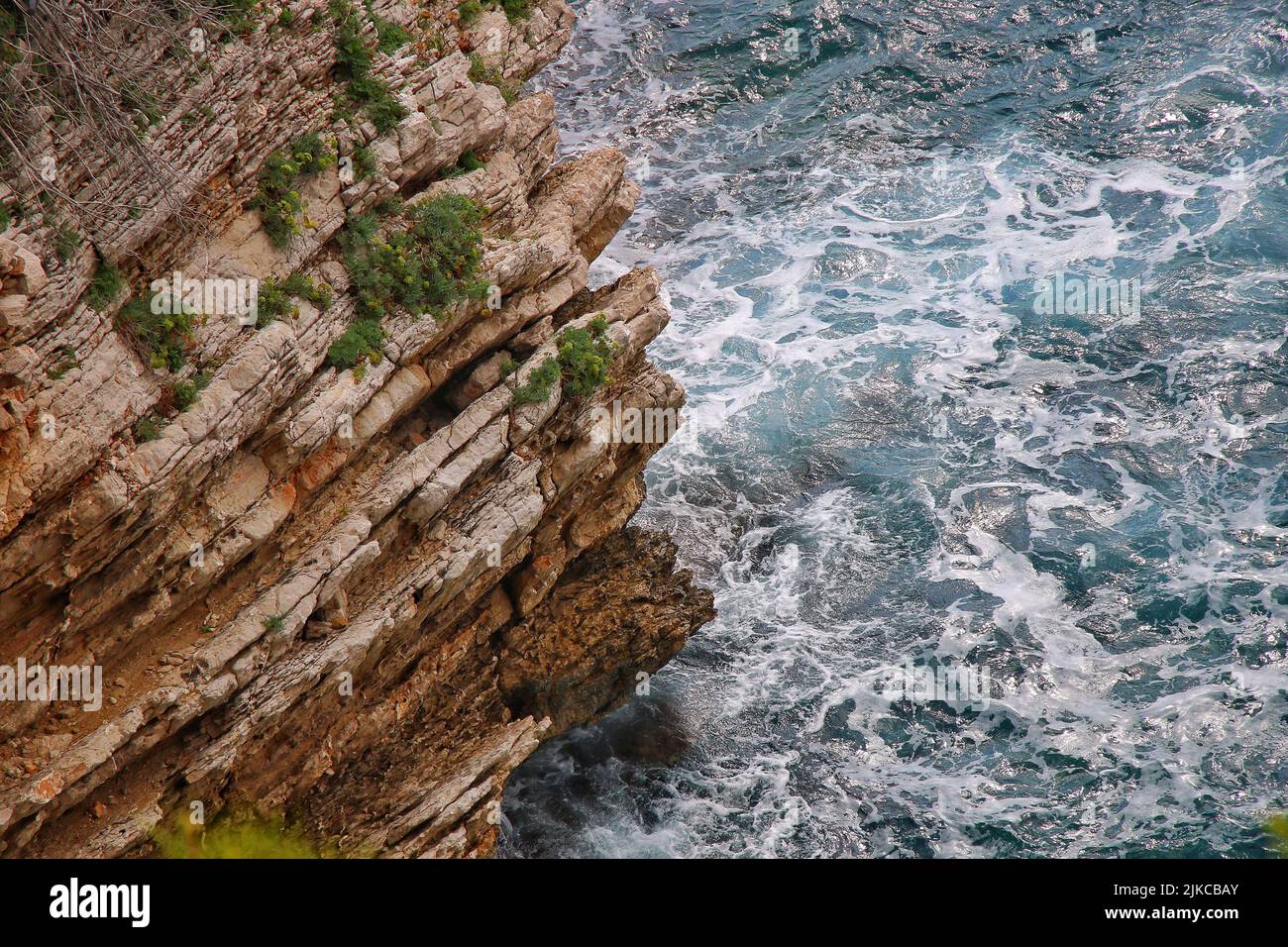 A close-up shot of strange-shaped rocks and sea waves hitting on them ...