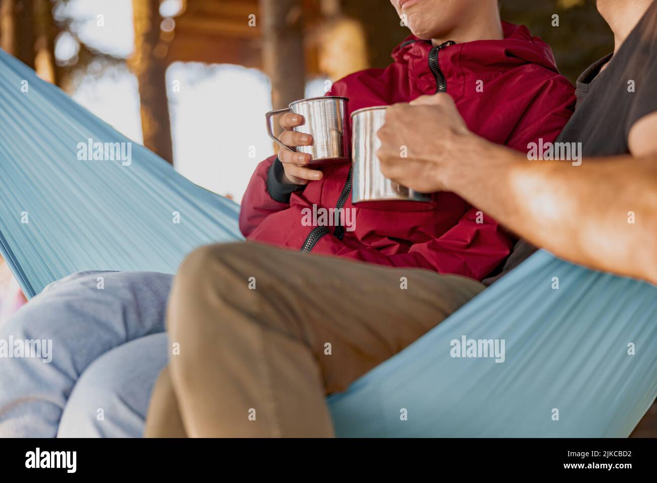 Steel cups of coffee in hands of man and woman. Couple hugging in ...