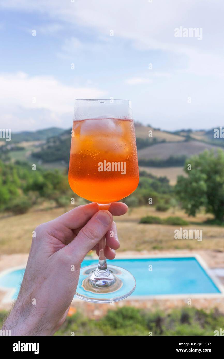 Hand holding an aperitif spritz cocktail with a beautiful italian view ...
