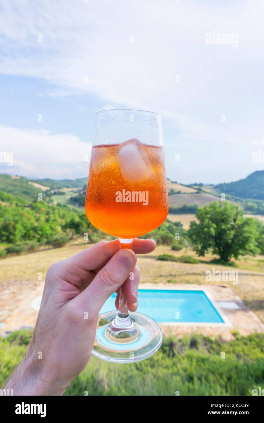 Hand holding an aperitif spritz cocktail with a beautiful italian view ...