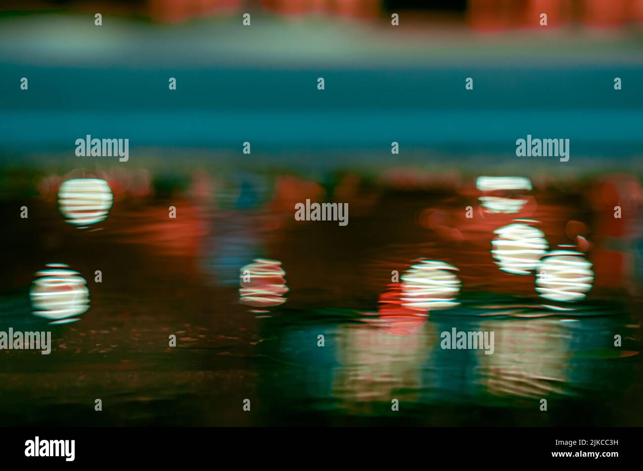 A reflection of illuminated lights on the puddle water Stock Photo - Alamy
