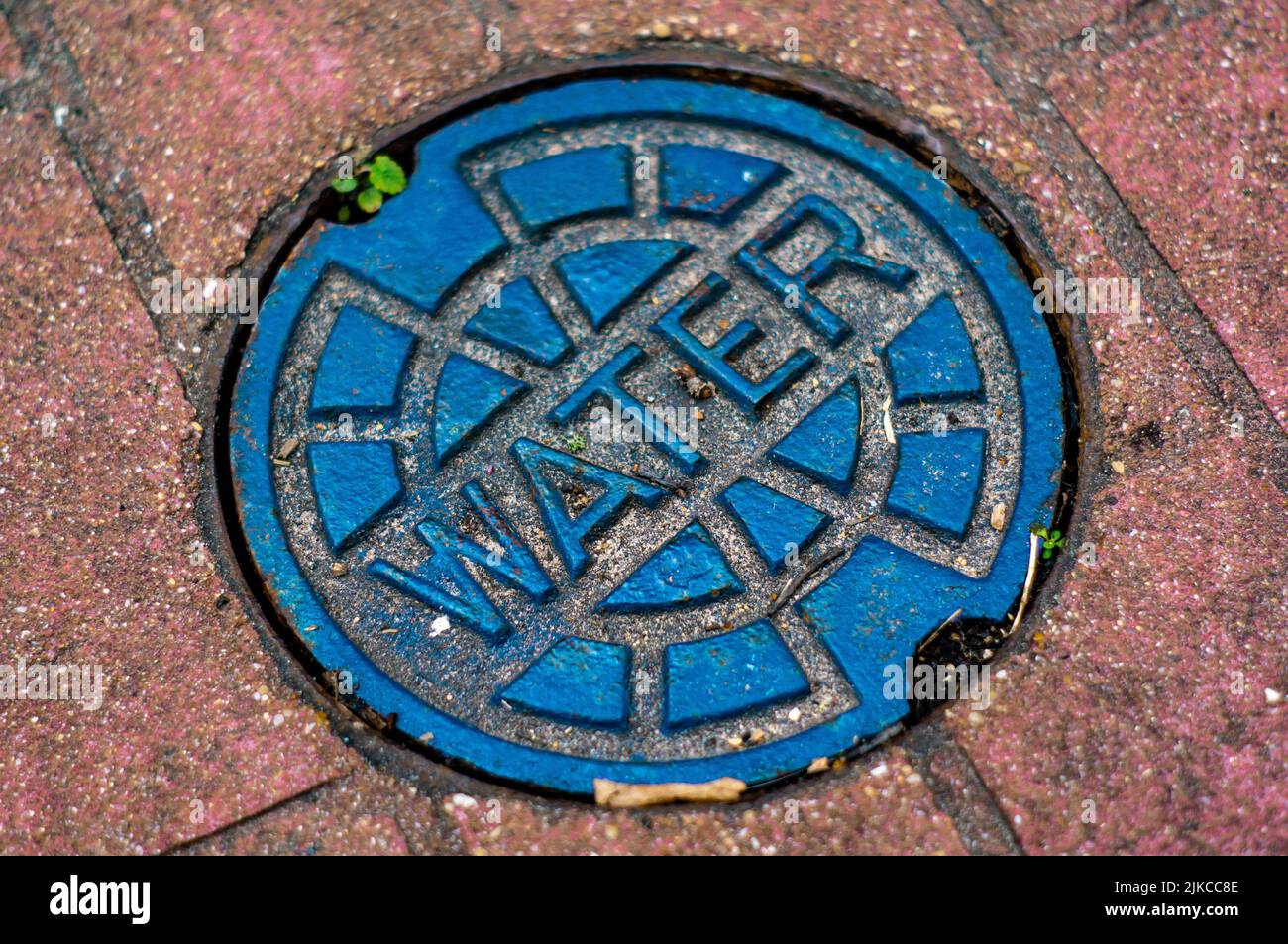 A blue water valve cover on a brick sidewalk Stock Photo - Alamy