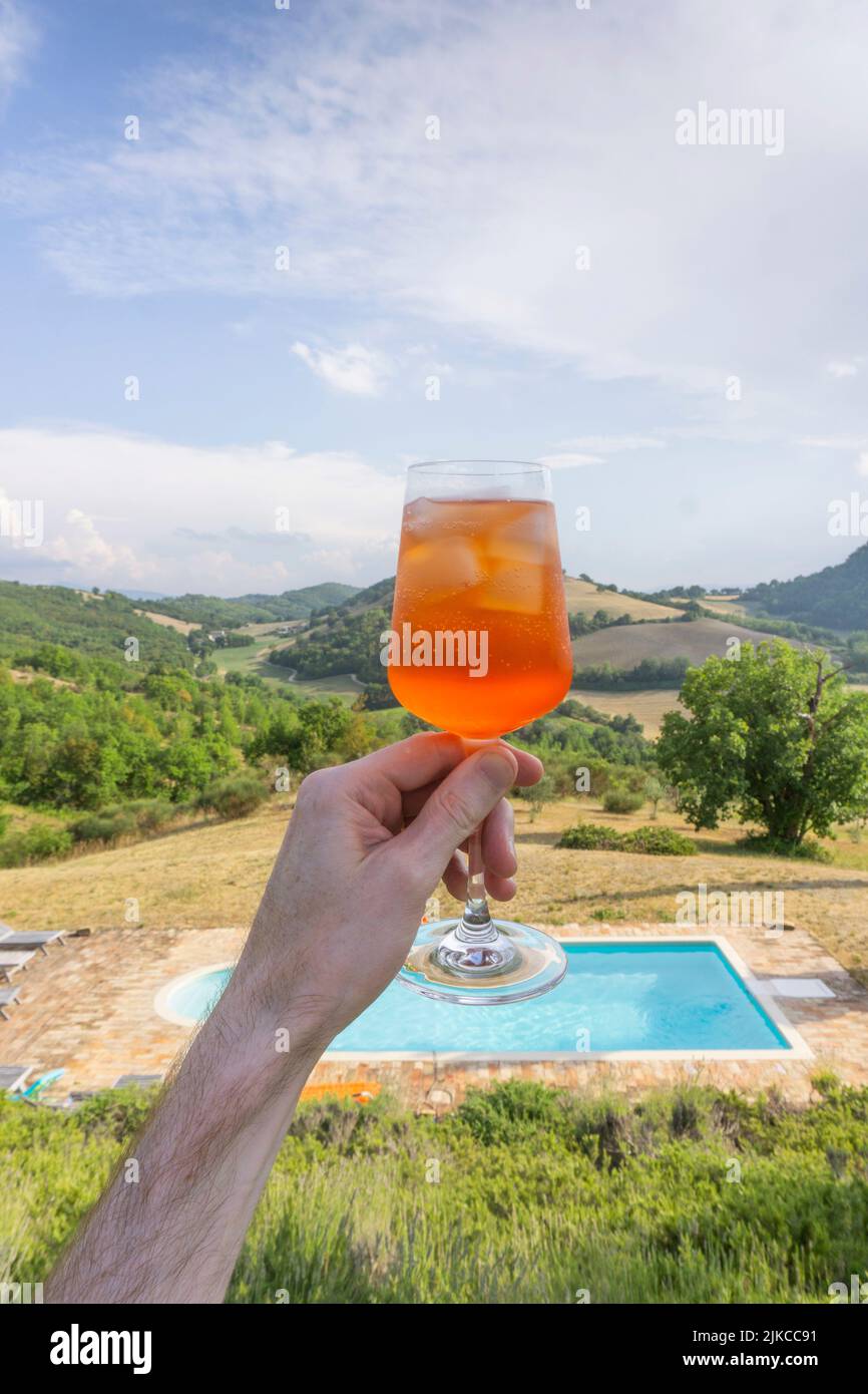 Hand holding an aperitif spritz cocktail with a beautiful italian view ...
