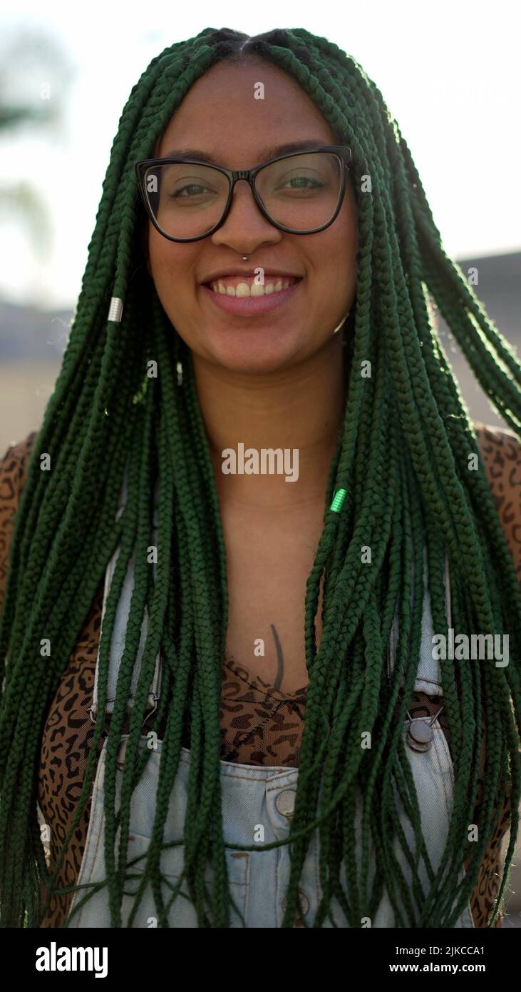 A happy black latin girl with green Box Braids hairstyle smiling at ...