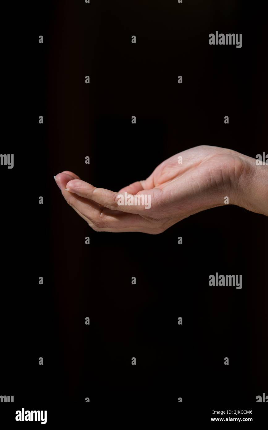 A vertical shot of a hand against the black background with copy space ...
