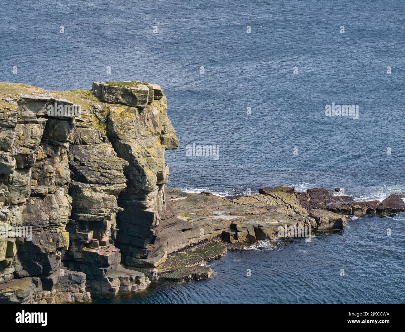 A large slab of rock at the top of a coastal cliff near Sandwick ...