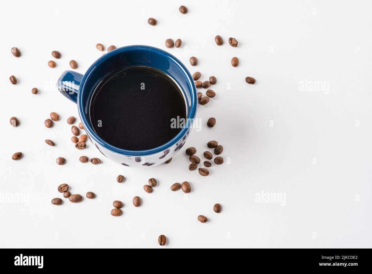 A top view of a cup of coffee with its beans on the white surface-great ...
