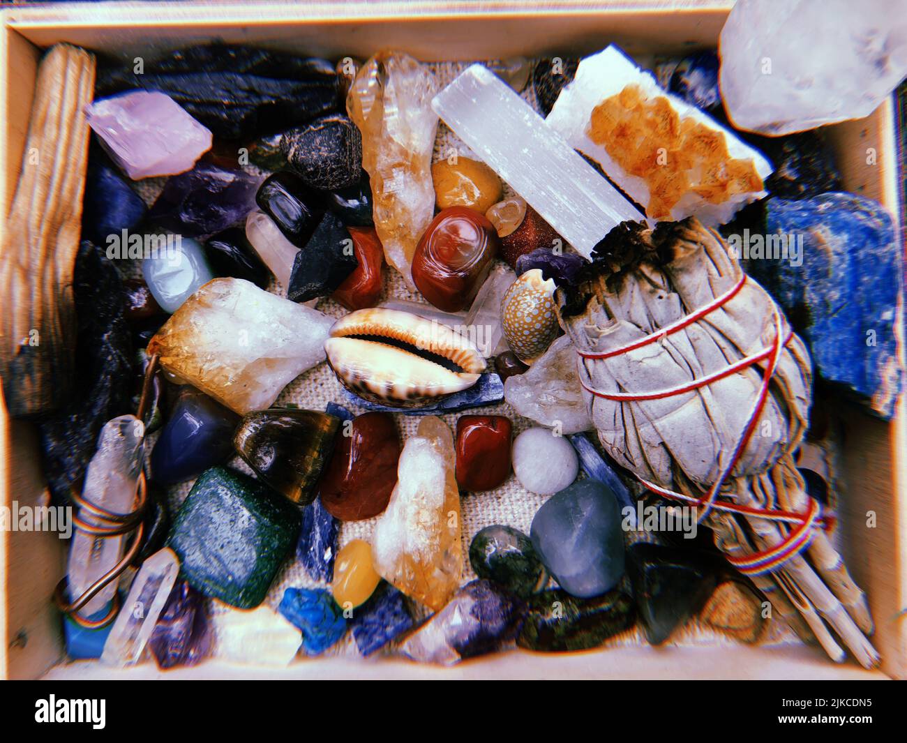 A box of crystal stones with palo santo and a smudge stick for ...