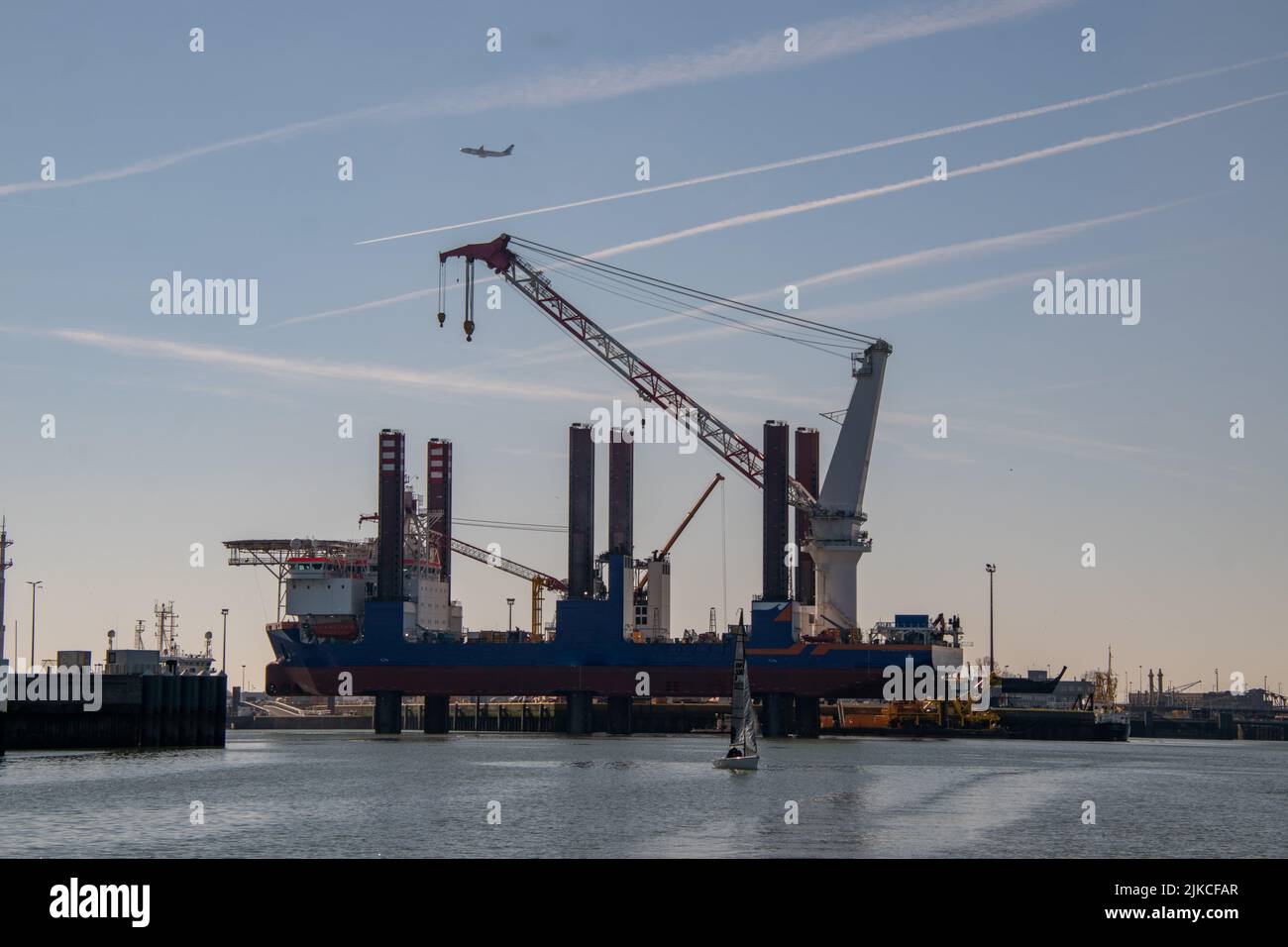 A plane flying over the industrial cranes at the port of Ostend Stock ...