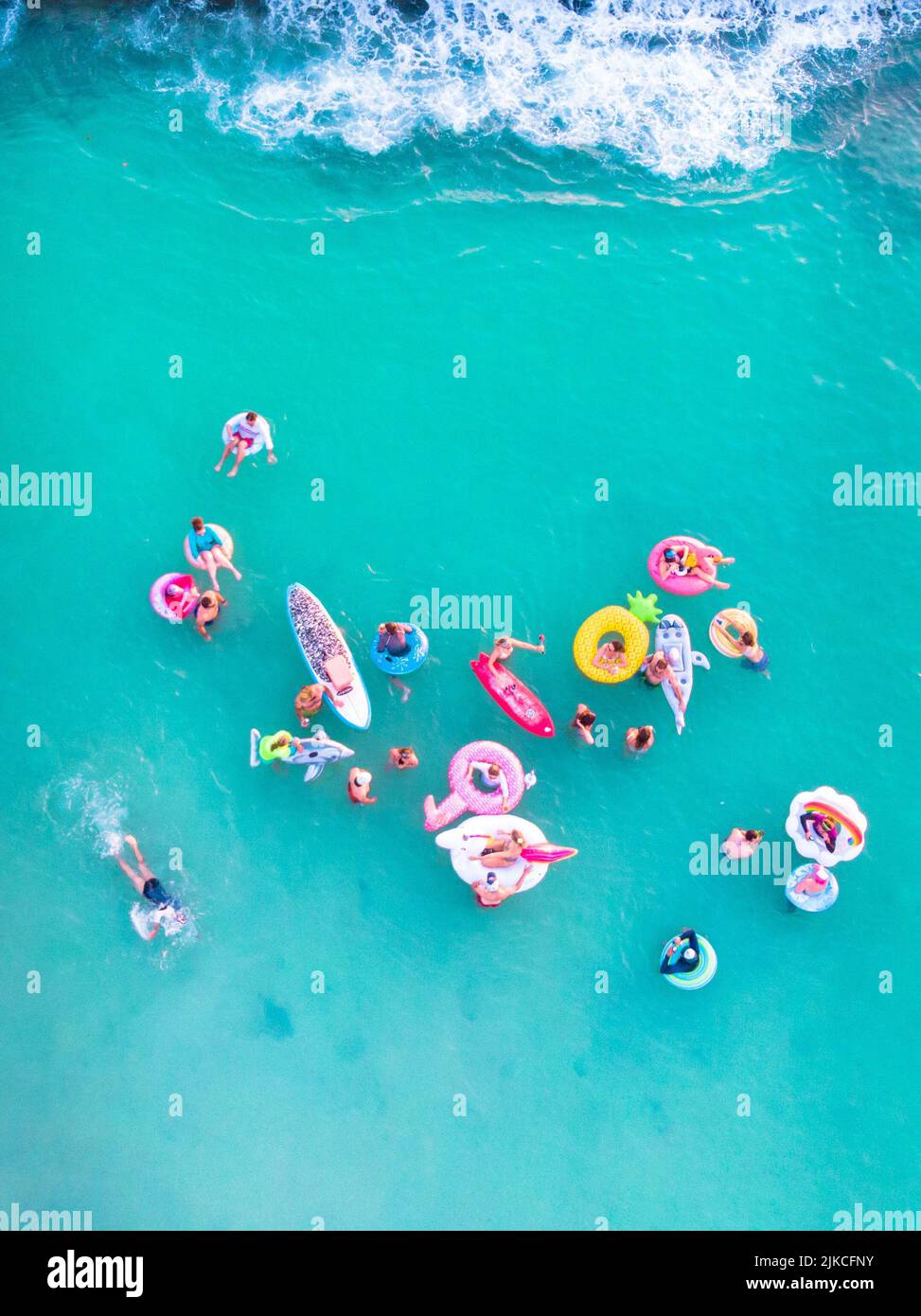 A vertical aerial top view of people with various colorful inflatable ...