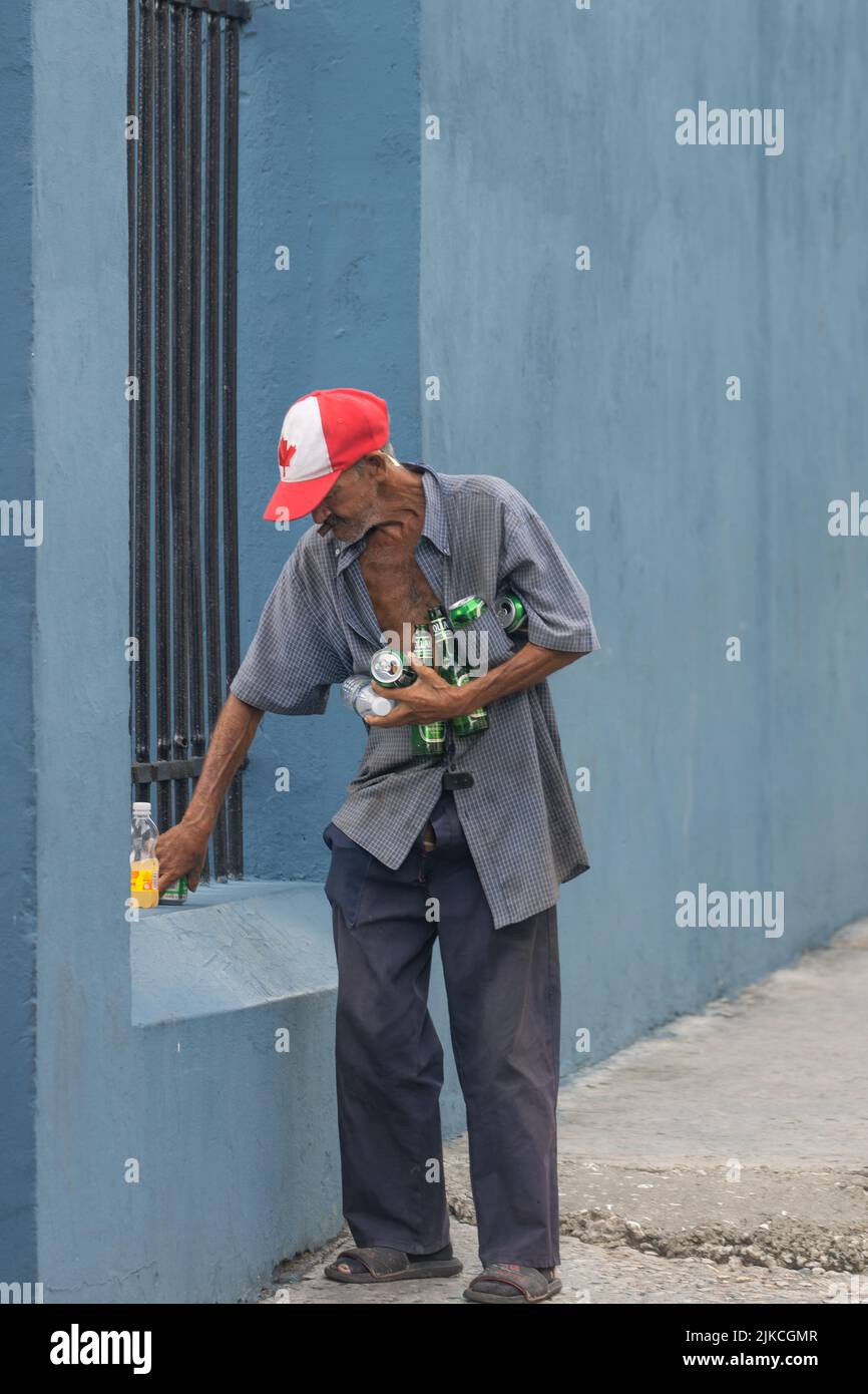 A vertical shot of an old poor man collecting food and drink in ...
