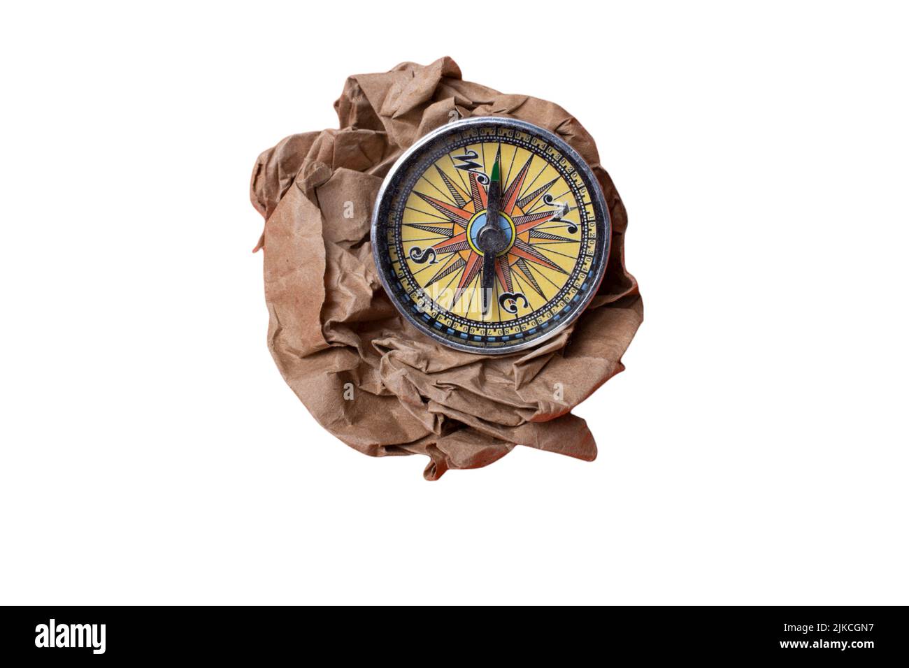 A navigational compass on a piece of crumpled brown paper with a white ...