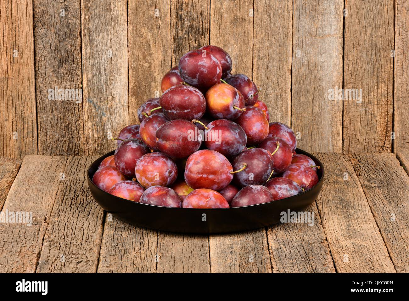 Plate of ripe plum isolated on dark wood background. High resolution ...