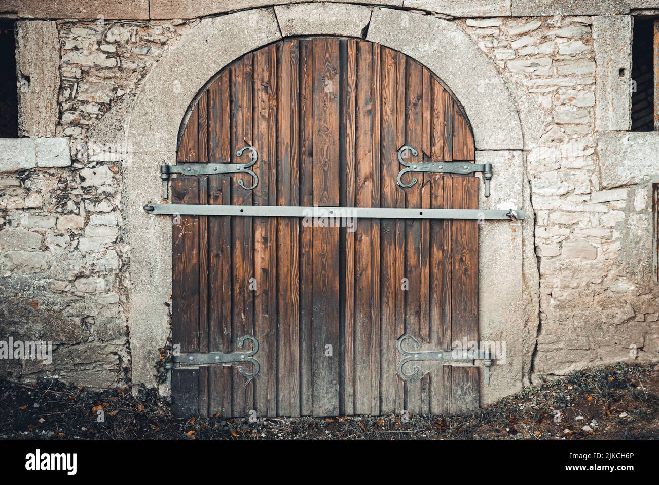 An old medieval arched wooden gate with metal elements and an iron ...