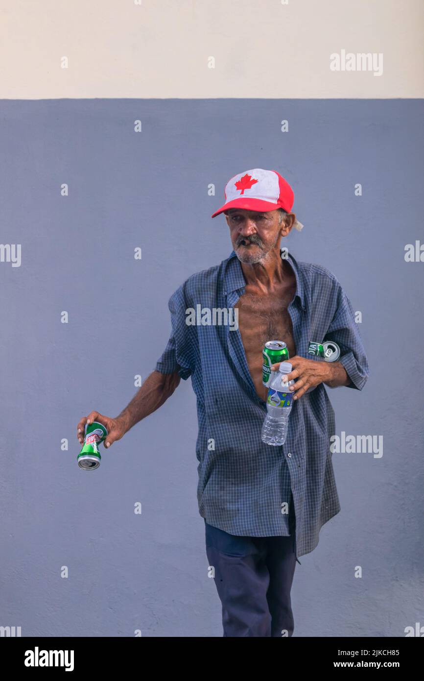 A vertical shot of a poor homeless man in a cap with Canadian flag ...