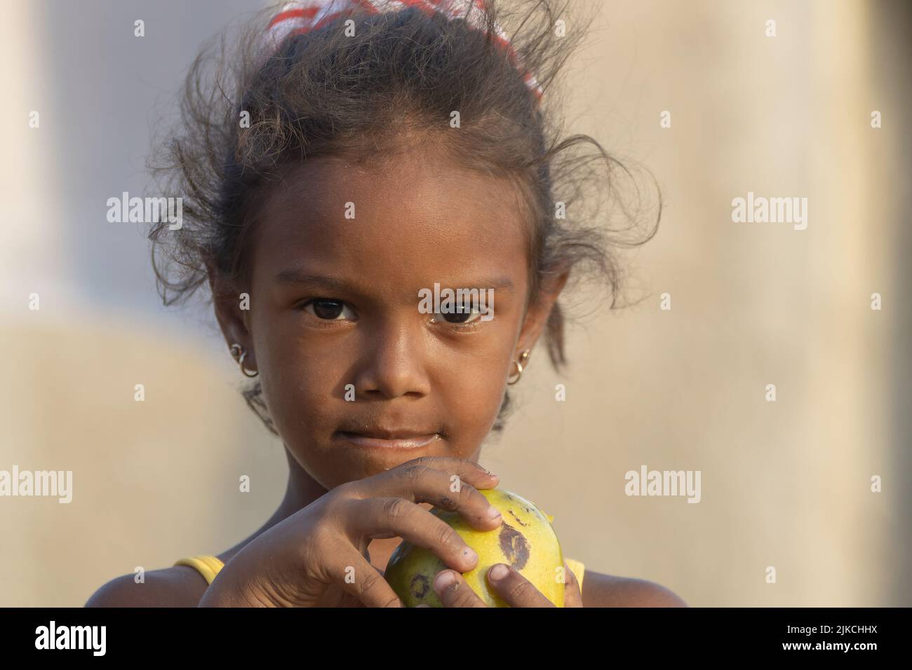 A poor Cuban girl eating mango Stock Photo - Alamy