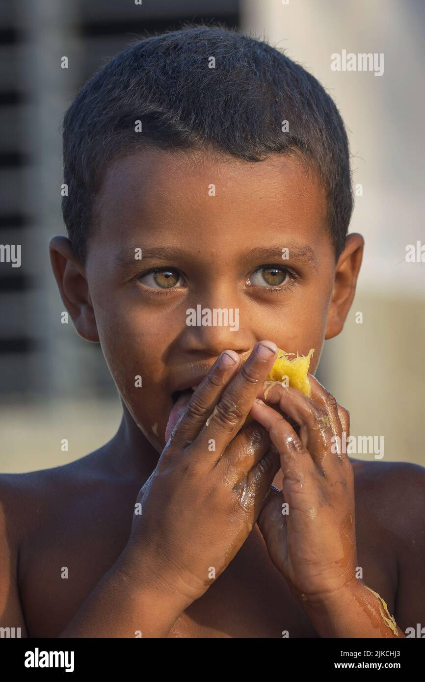 A poor Cuban girl eating mango Stock Photo - Alamy