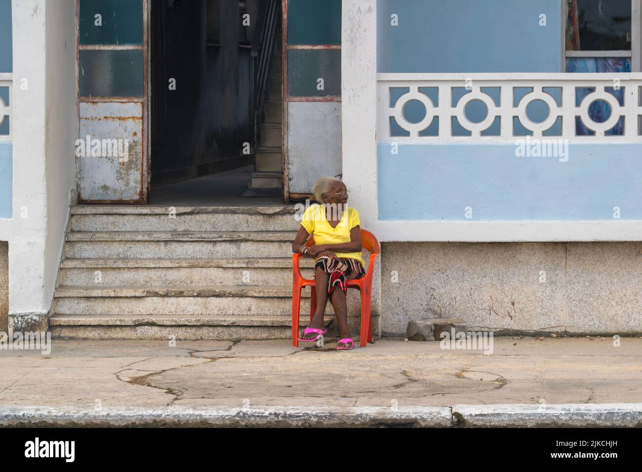 An elderly lady getting fresh air on the sidewalk of the street in ...