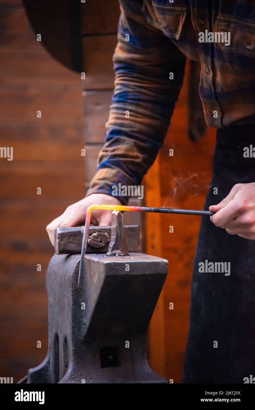 A man striking hot iron with a hammer on the Anvil Stock Photo - Alamy