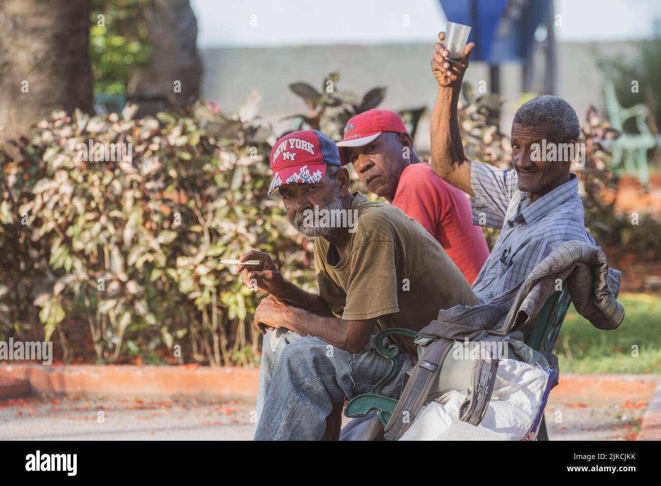 a closeup of men sitting on the outdoor bench smoking and cheering with ...