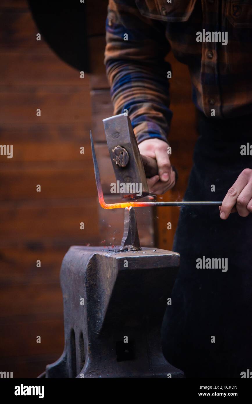 A man striking hot iron with a hammer on the Anvil Stock Photo - Alamy