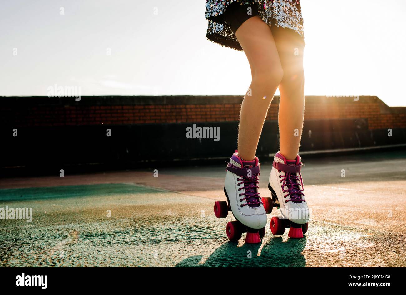 Childs legs with roller boots in in a sequin dress dancing at sunset ...