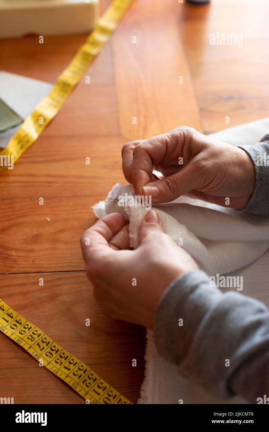 A female carefully sewing white cloth Stock Photo - Alamy