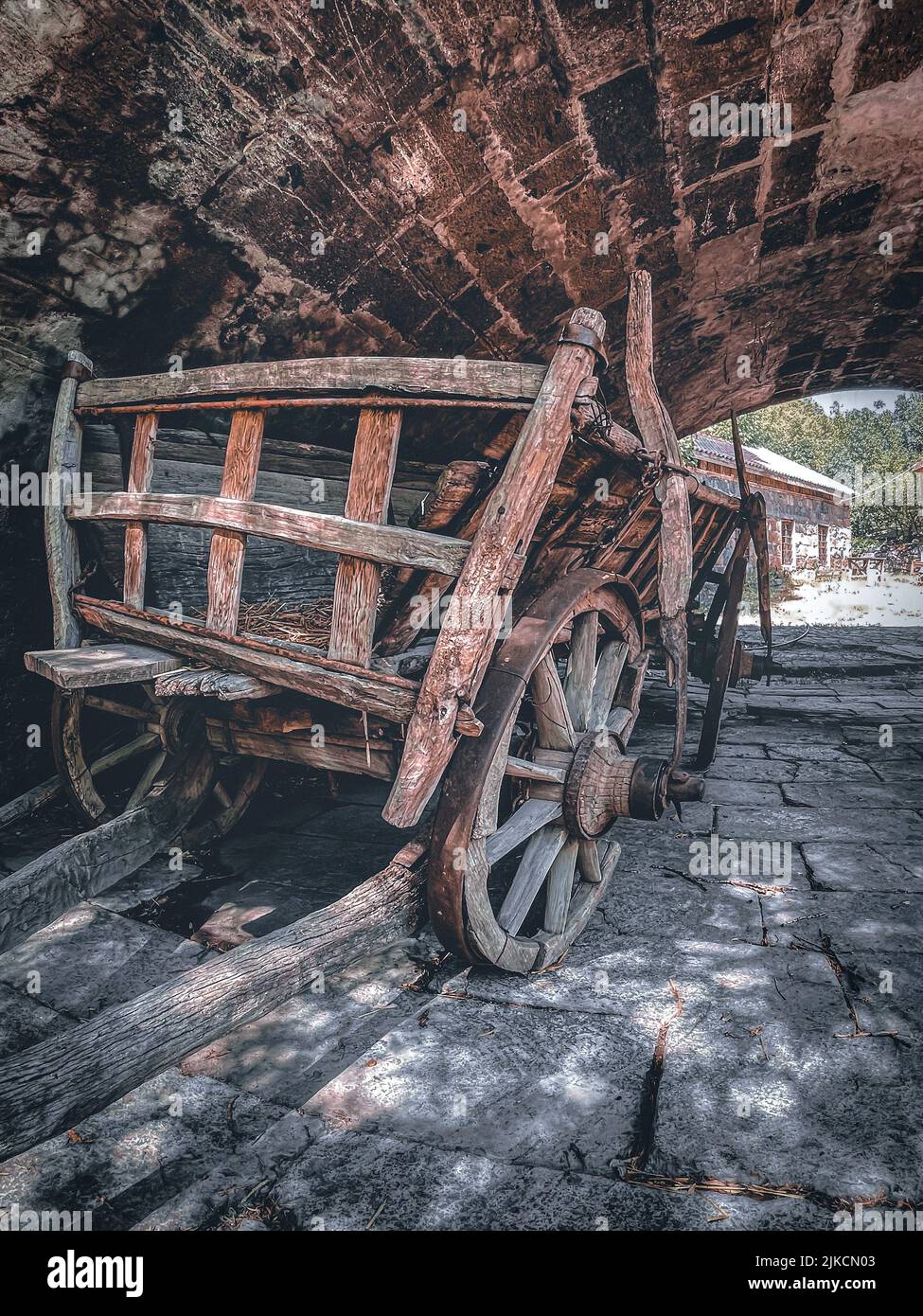 a vertical shot of a Vintage wooden cart under a stone arch in an old ...