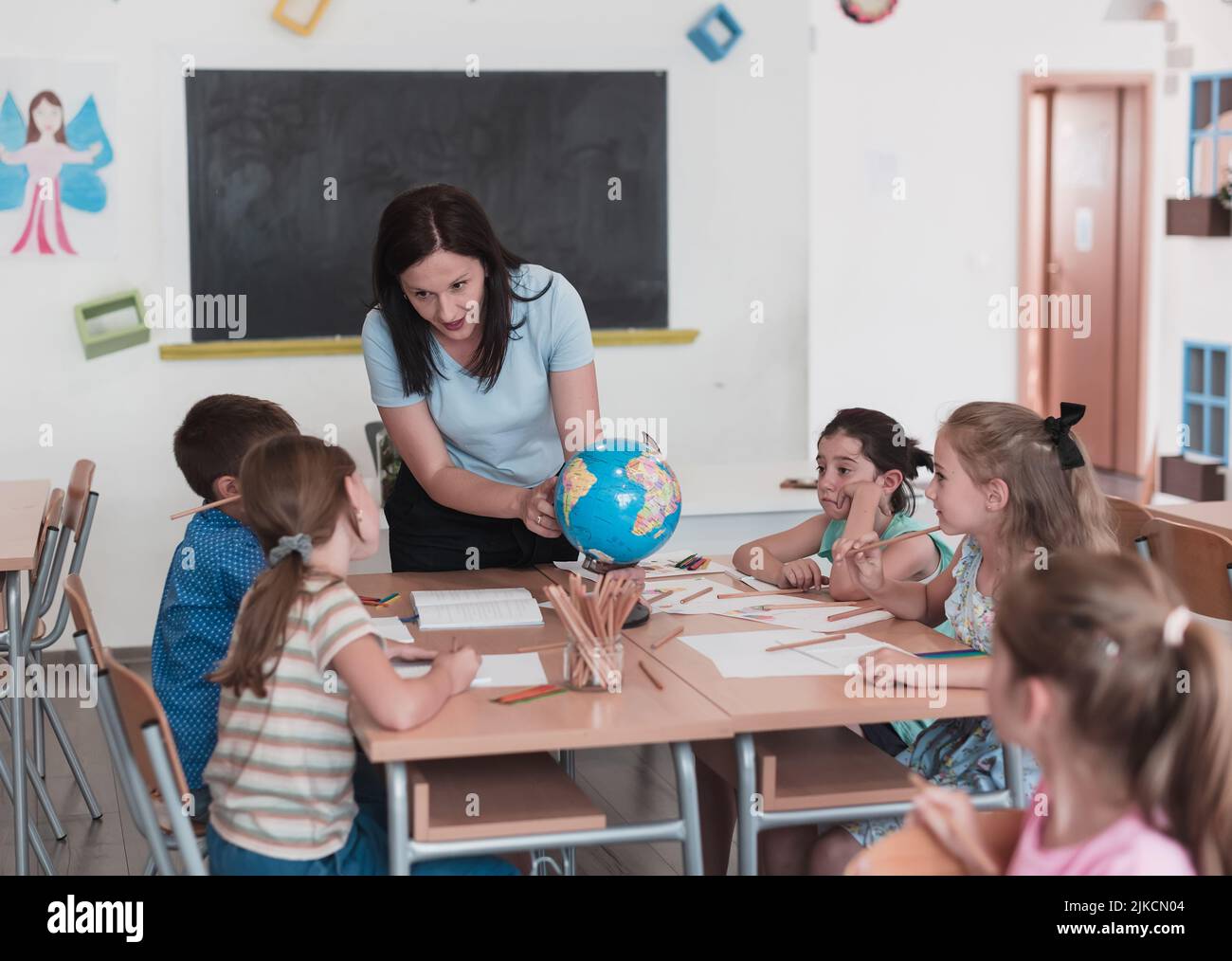 Female teacher with kids in geography class looking at globe. Side view ...