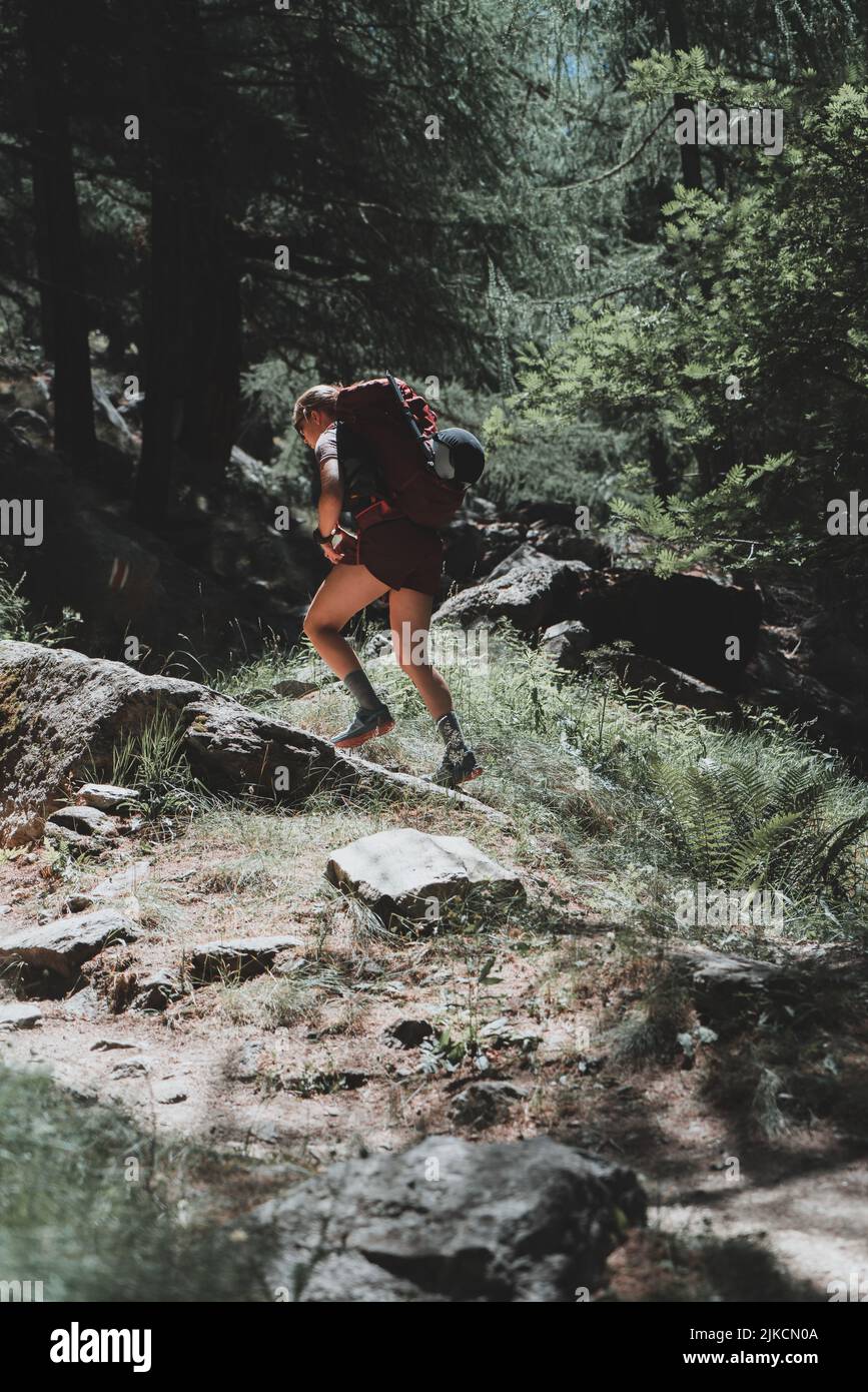 Young female hiker walking uphill with heavy overnight-ready backpack ...